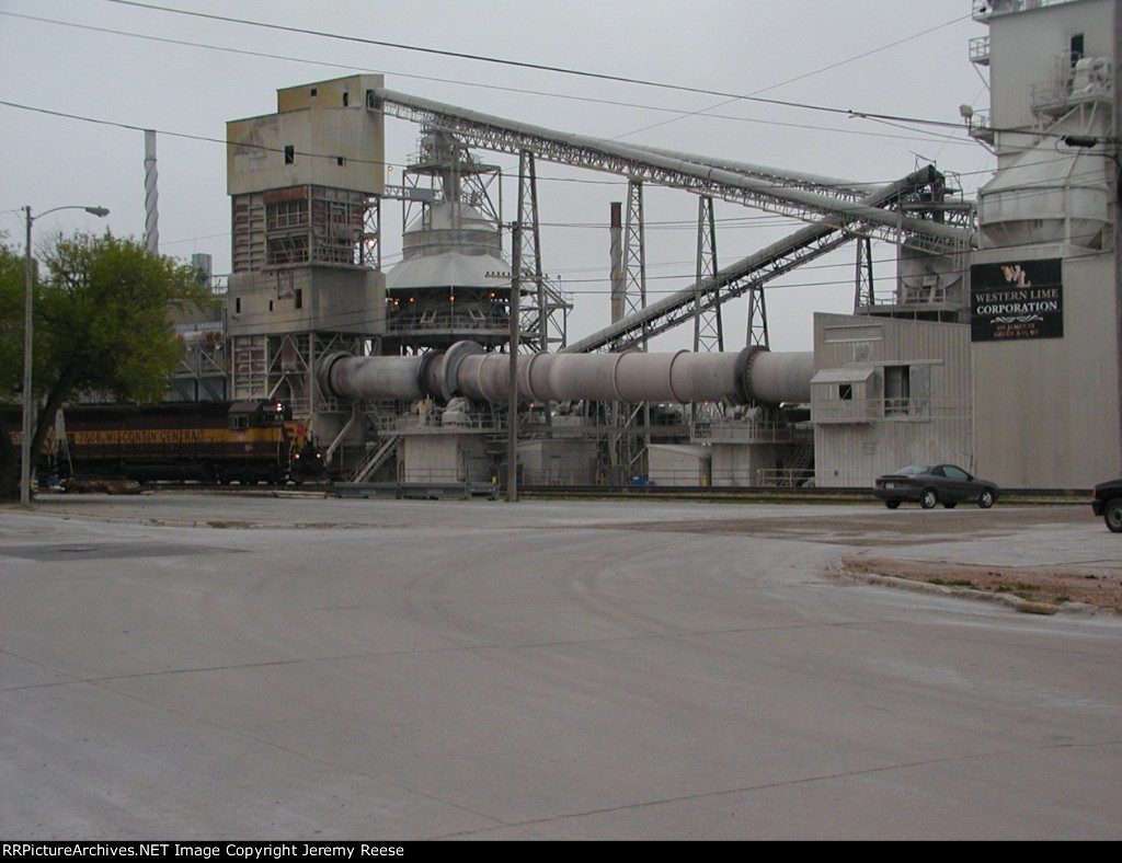 WC 7506 looks small next to rock complex on Fox River next to yard